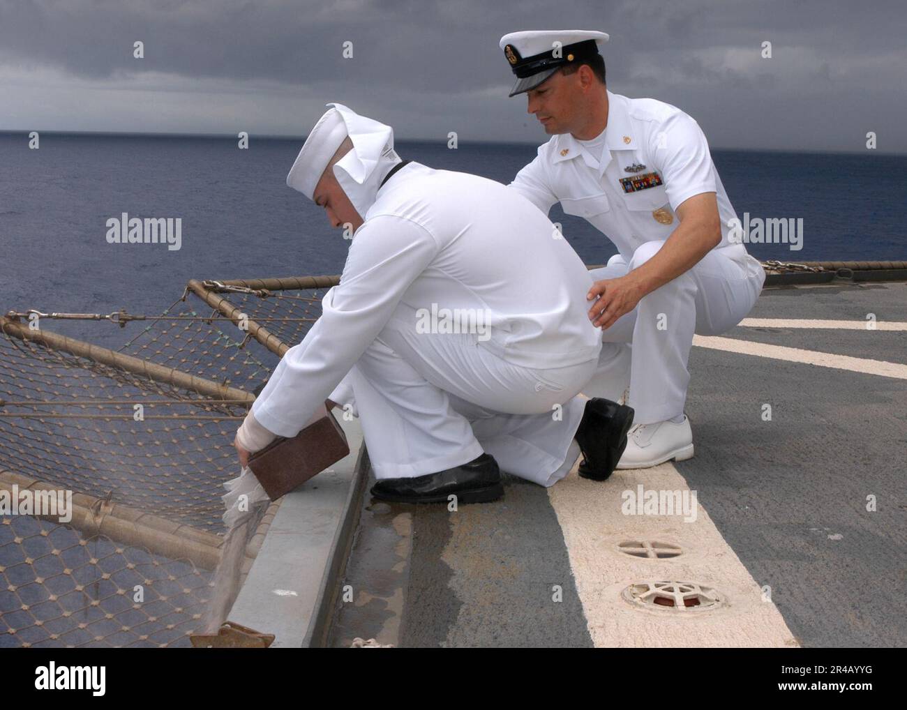 US Navy Chief Master-at-Arms assists Hull Technician 3rd Class while ...