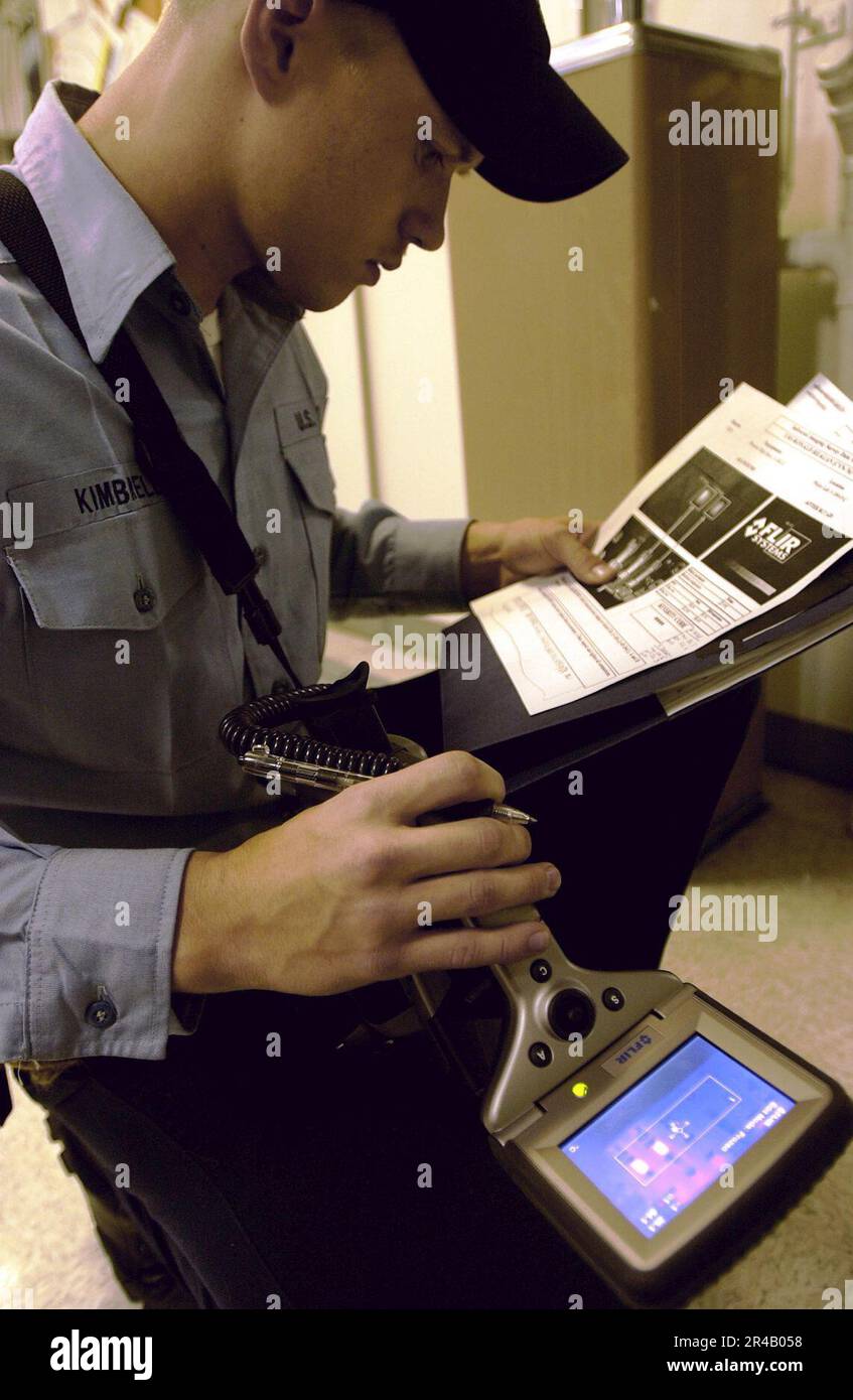US Navy Electrician's Mate Fireman checks the fuse temperature on an ...