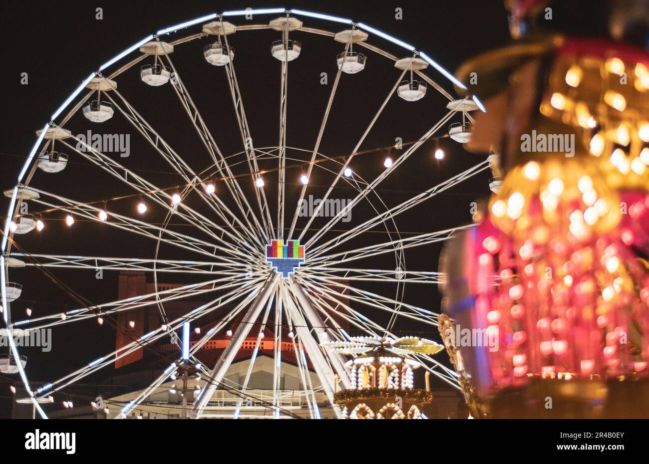 A vibrant night scene of a large ferris wheel situated in the middle of ...