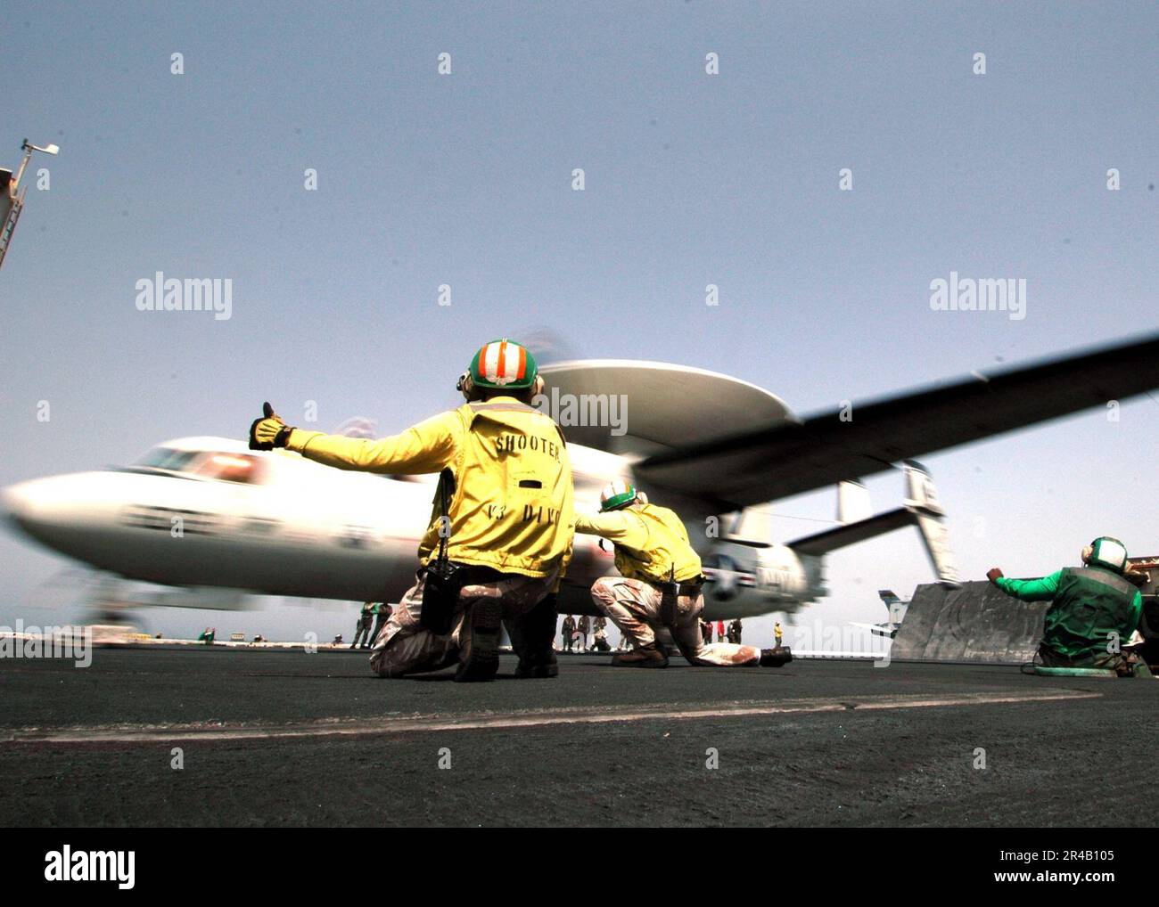 US Navy Two flight deck shooters give the clear to launch signal as an ...