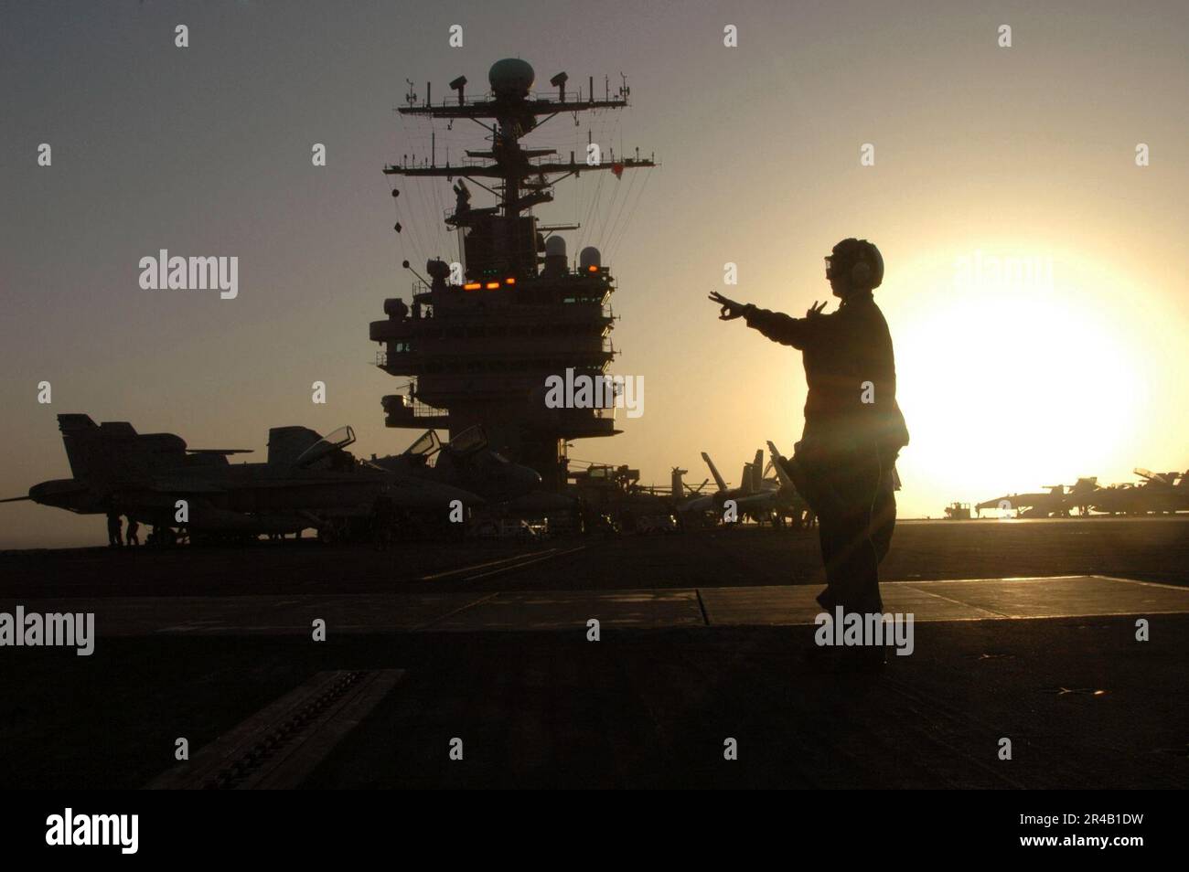US Navy A plane captain uses hand signals to communicate with the ...