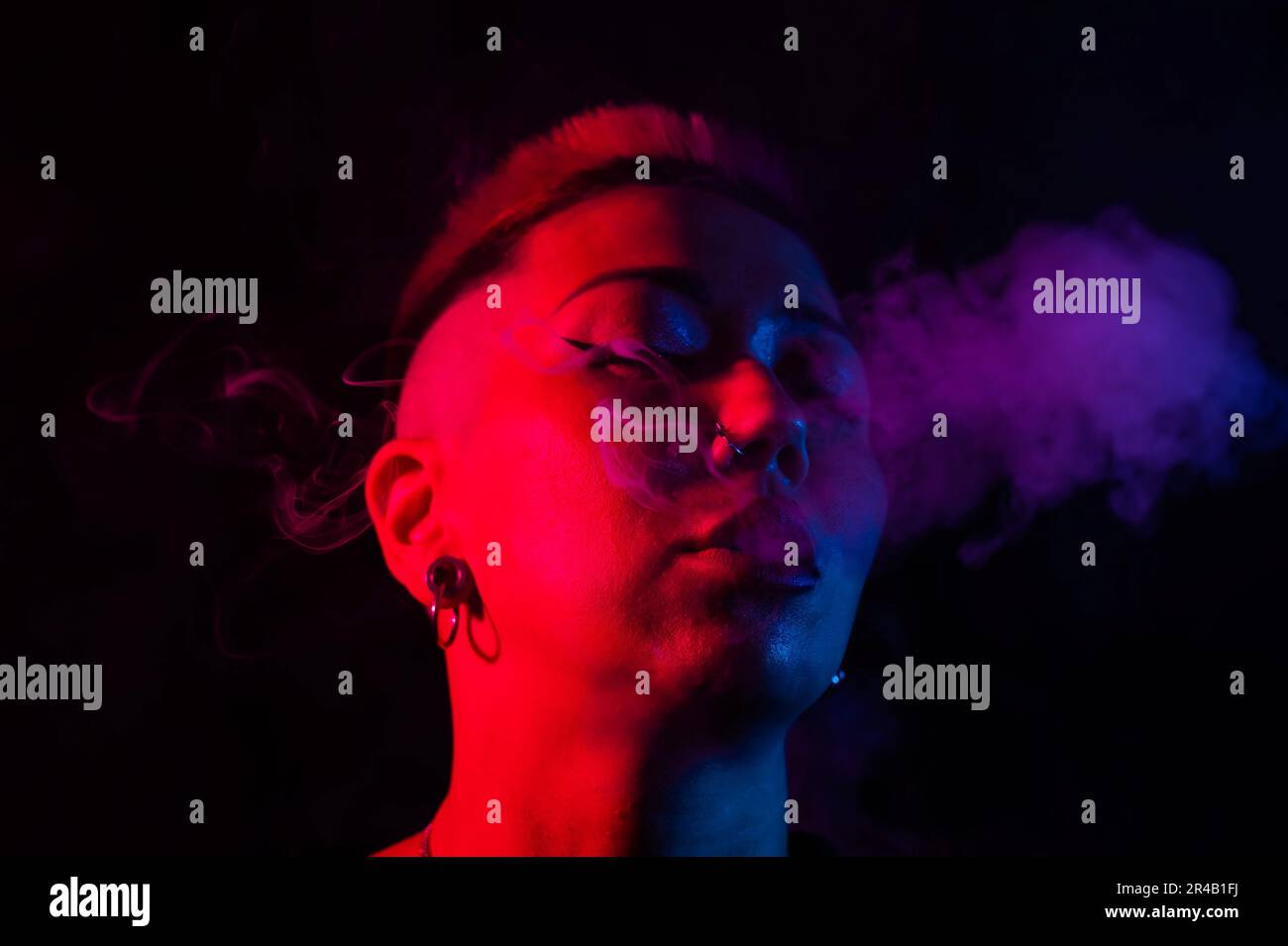 Close up portrait of asian woman with short hair smoking in neon light ...