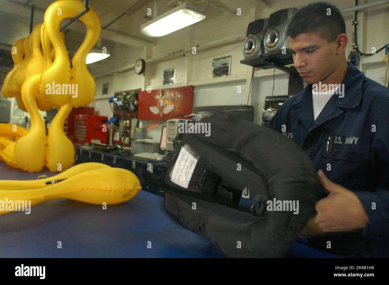 US Navy Aircrew Survival Equipmentman Airman inspects a life preserver ...