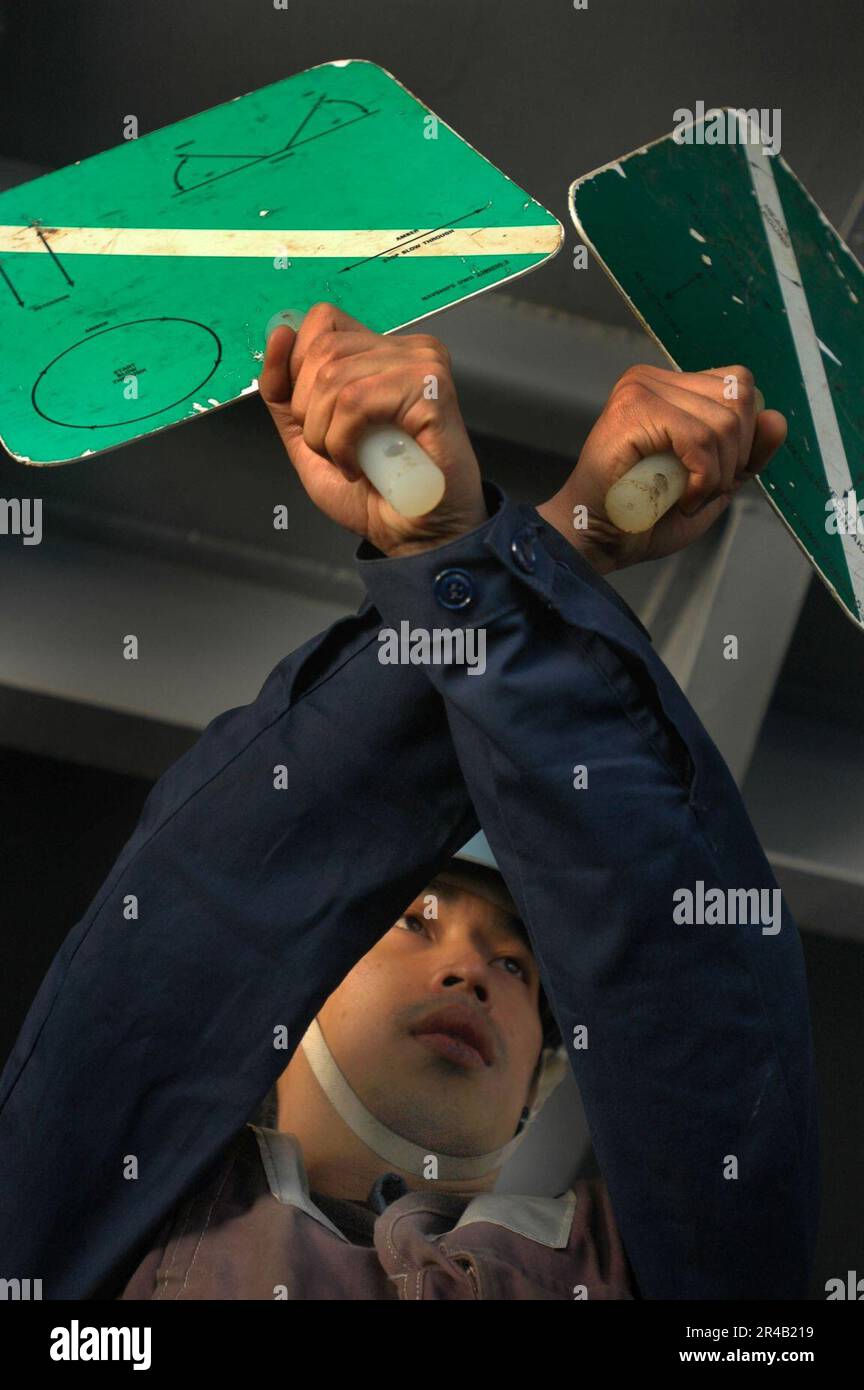 US Navy Seaman signals that all lines have been detached following a ...