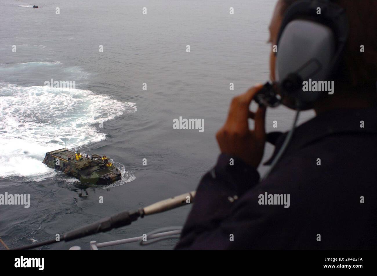US Navy Seaman uses a sound-powered telephone to reply the progress of ...