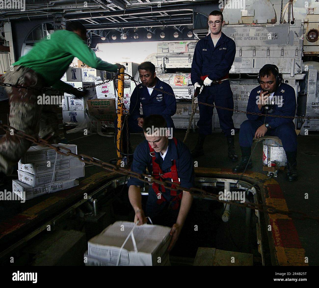 US Navy Supply Department personnel use a vertical conveyer to lower ...