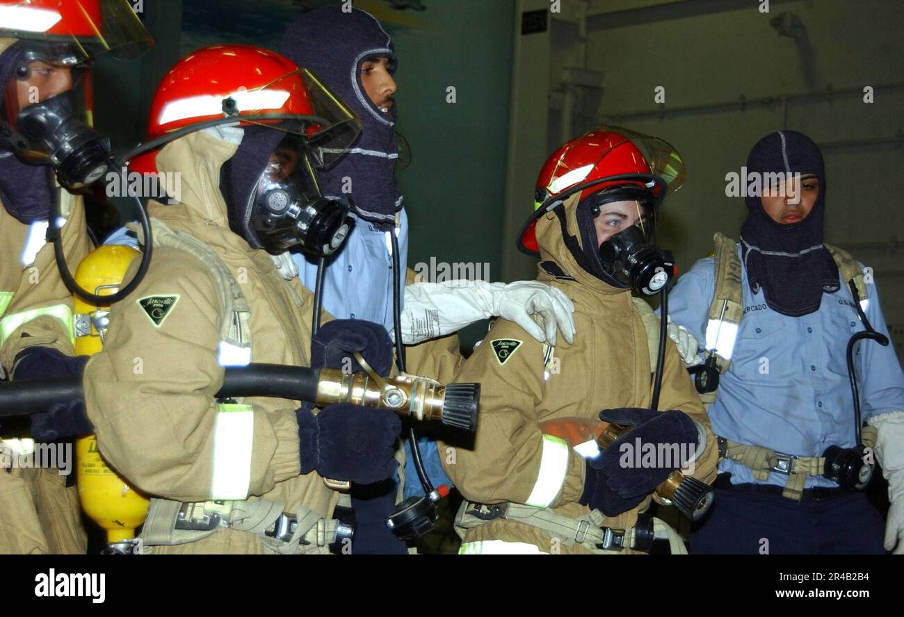 US Navy Sailors on a secondary hose team stand ready to relieve the ...