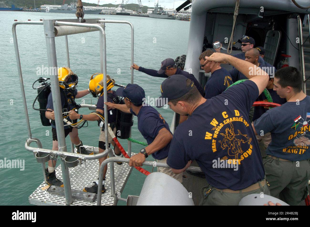 US Navy Dive Supervisor Chief Hull Technician foreground, monitors the ...