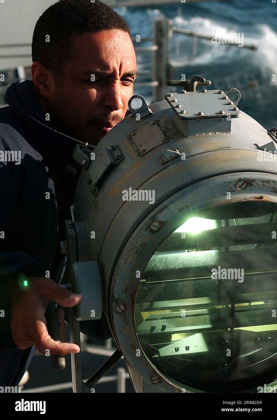 US Navy Quartermaster 1st Class communicates by flashing light from the ...