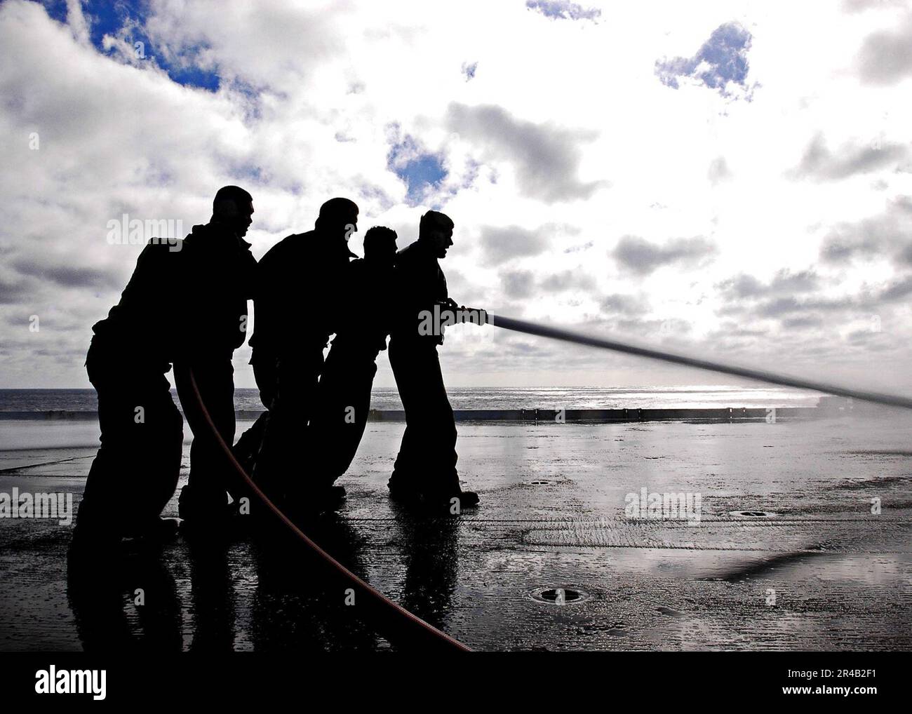 US Navy Sailor's assigned to Air Department, spray down the flight deck ...