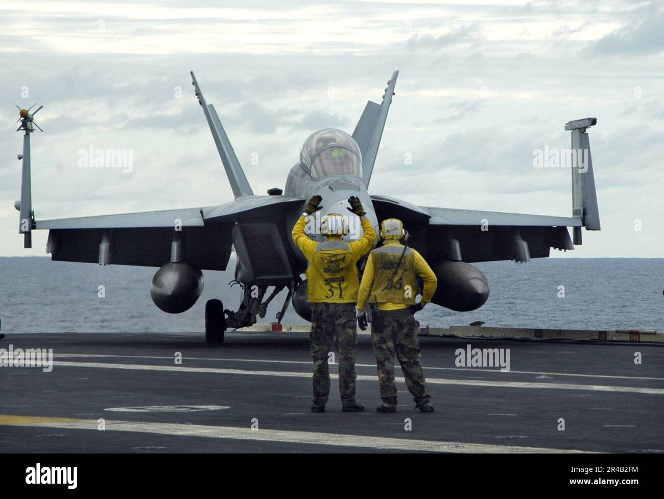 US Navy Aircraft directors signal for an F-A-18F Super Hornet to taxi ...