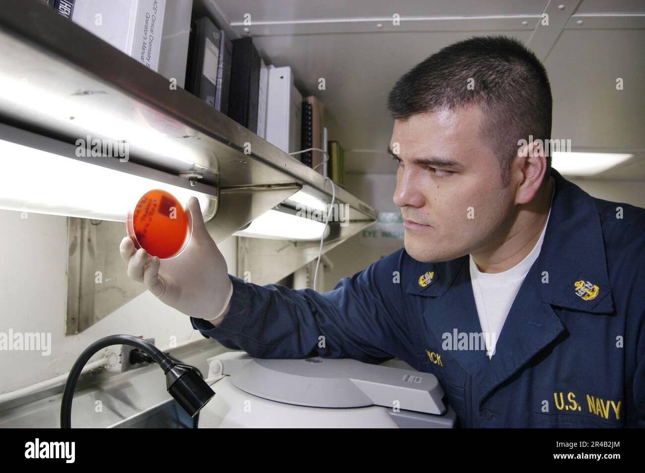 US Navy Chief Hospital Corpsman examines a culture dish aboard the ...