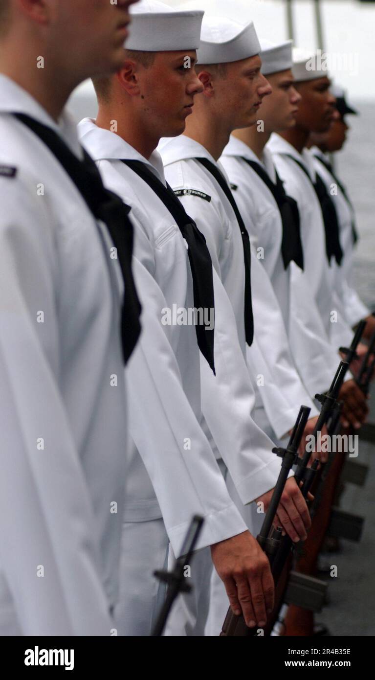 US Navy Honor Guard members stand at parade rest during a burial at sea ...