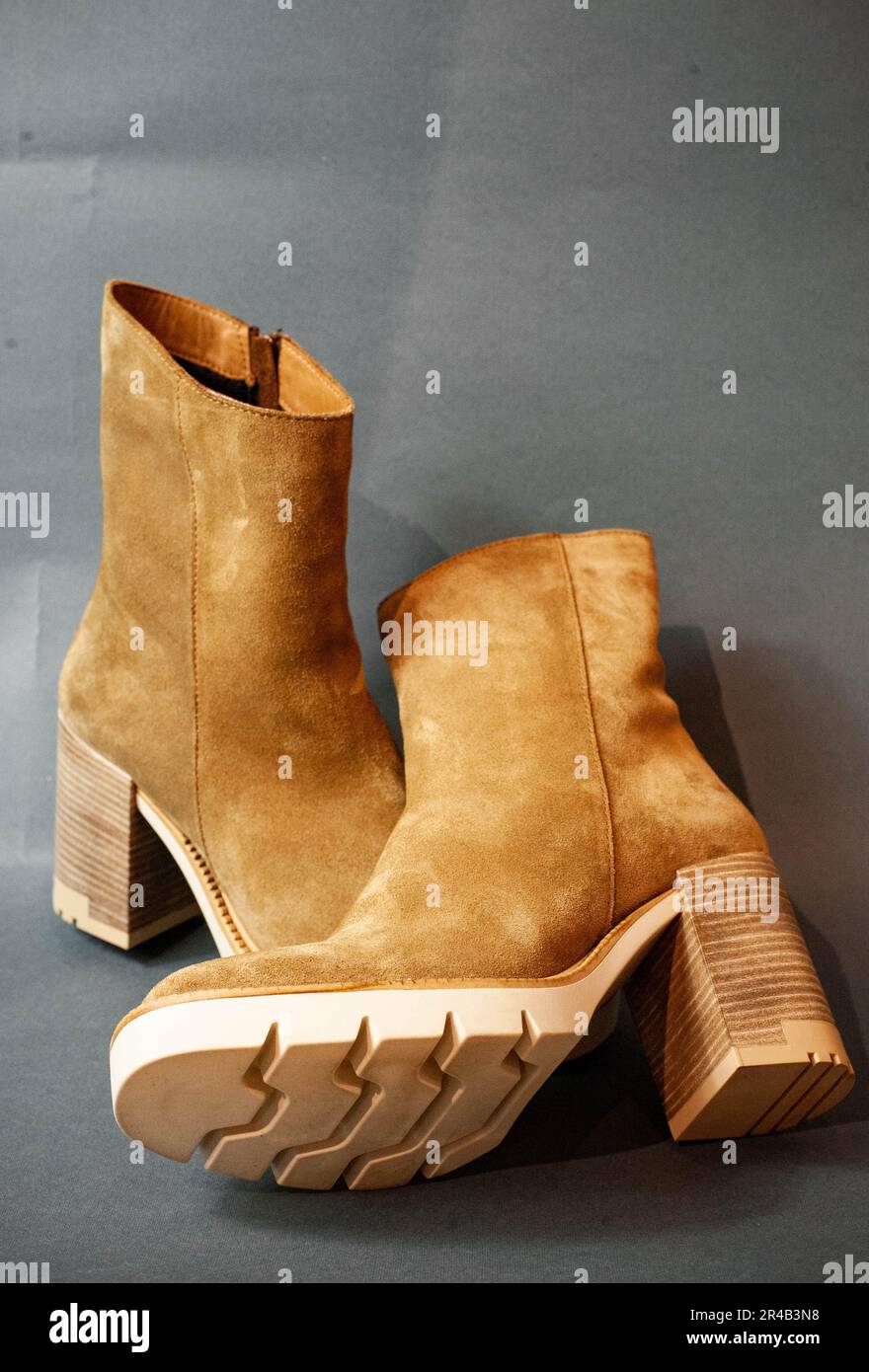 A stylish pair of brown leather boots rest on a vibrant blue background ...