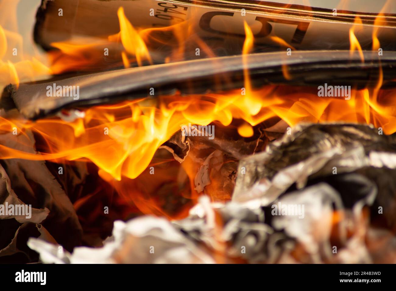 Close-up of a fire burning inside a container containing newspaper ...