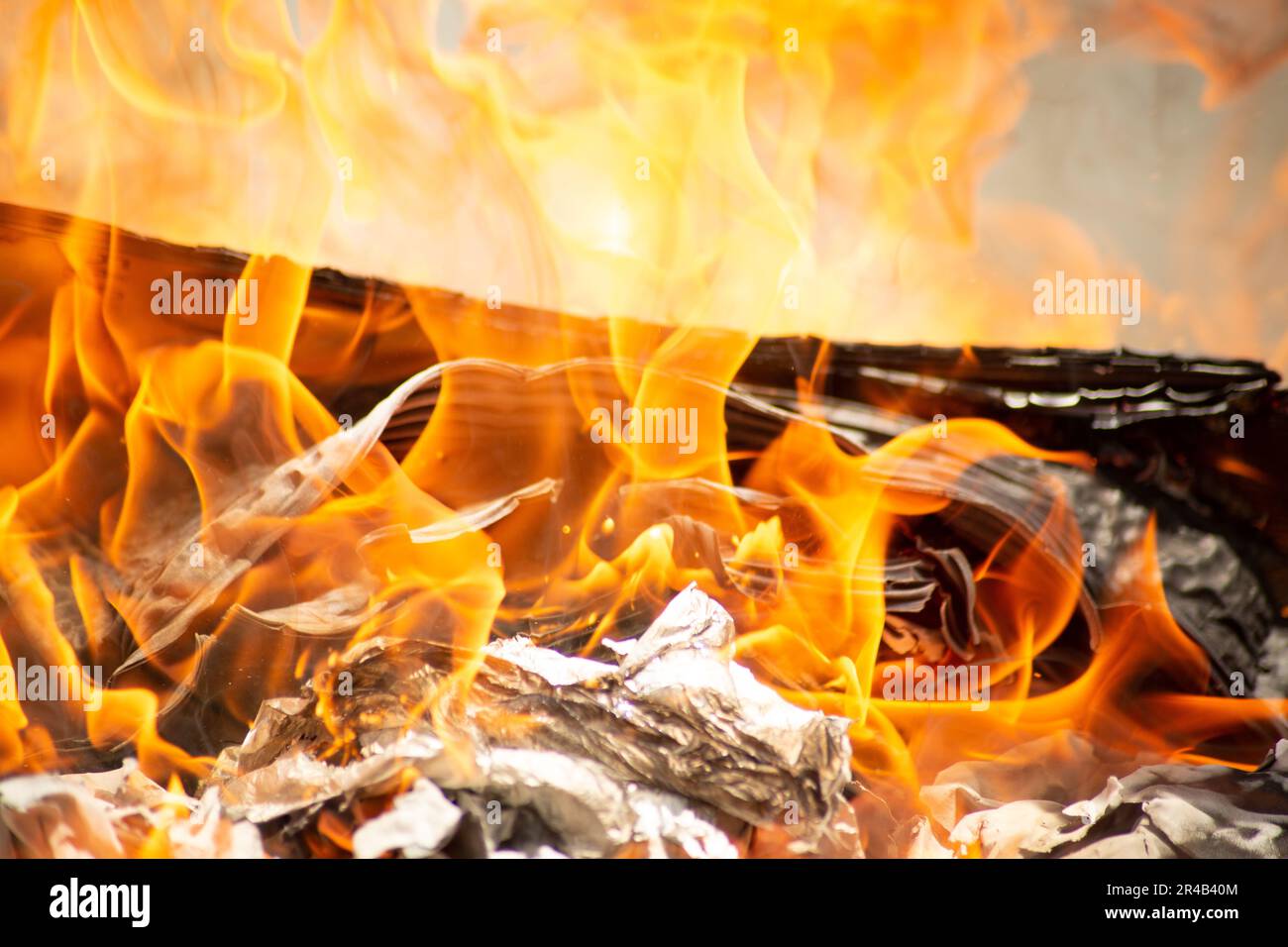 A close-up image of a trash can engulfed in flames, producing smoke and ...