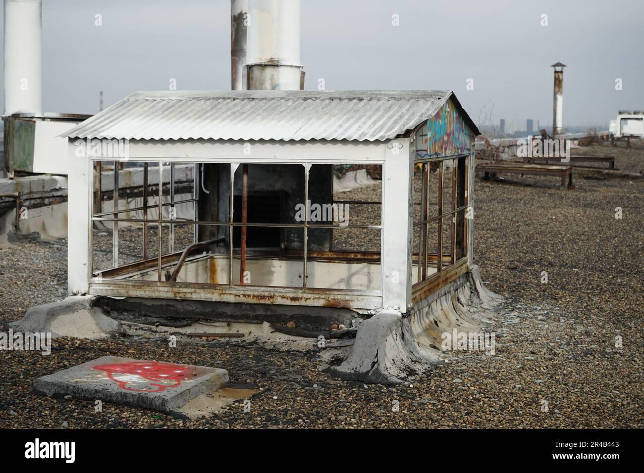 A small structure situated atop a field of gravel, adjacent to a larger ...