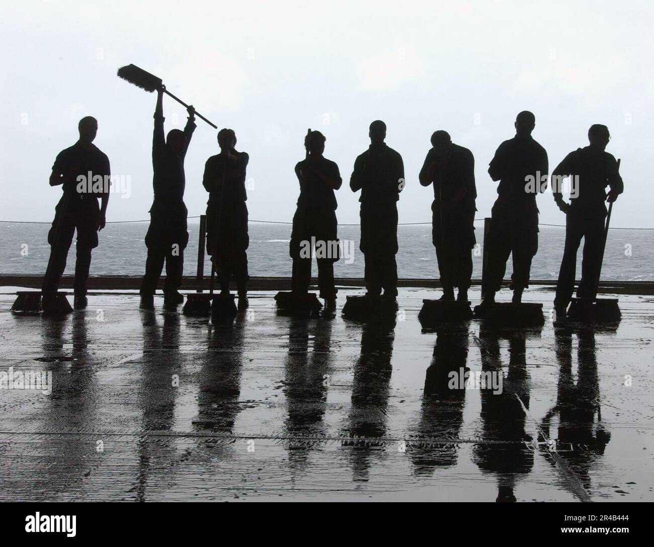 US Navy Sailors use brushes to scrub down the deck on the hangar bay ...