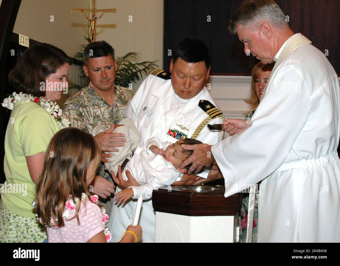 US Navy Lt. Cmdr. holds his son during a baptism ceremony performed by ...