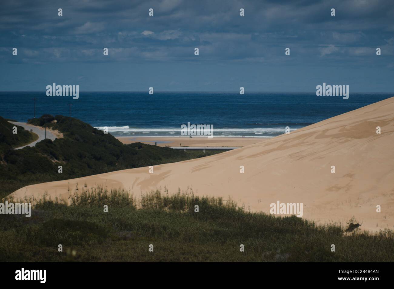 A lone individual strides across an expansive beach, the sun reflecting ...