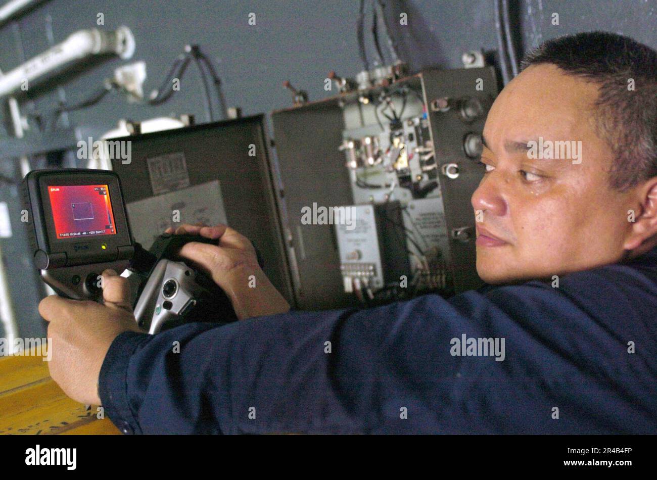 US Navy Electrician's Mate 2nd Class checks a power panel for hot spots ...