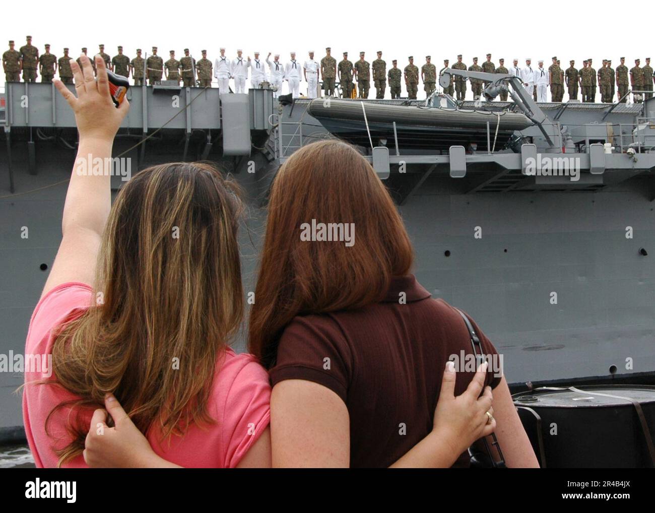 US Navy Two women wave goodbye to the Sailors and Marines manning the rails of the amphibious ...