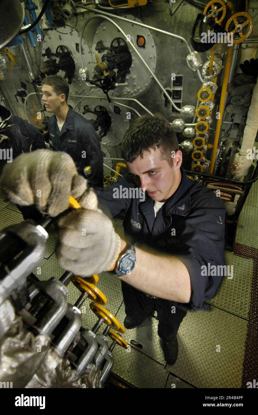 US Navy Machinist's Mate 3rd Class aligns an auxiliary steam valve ...