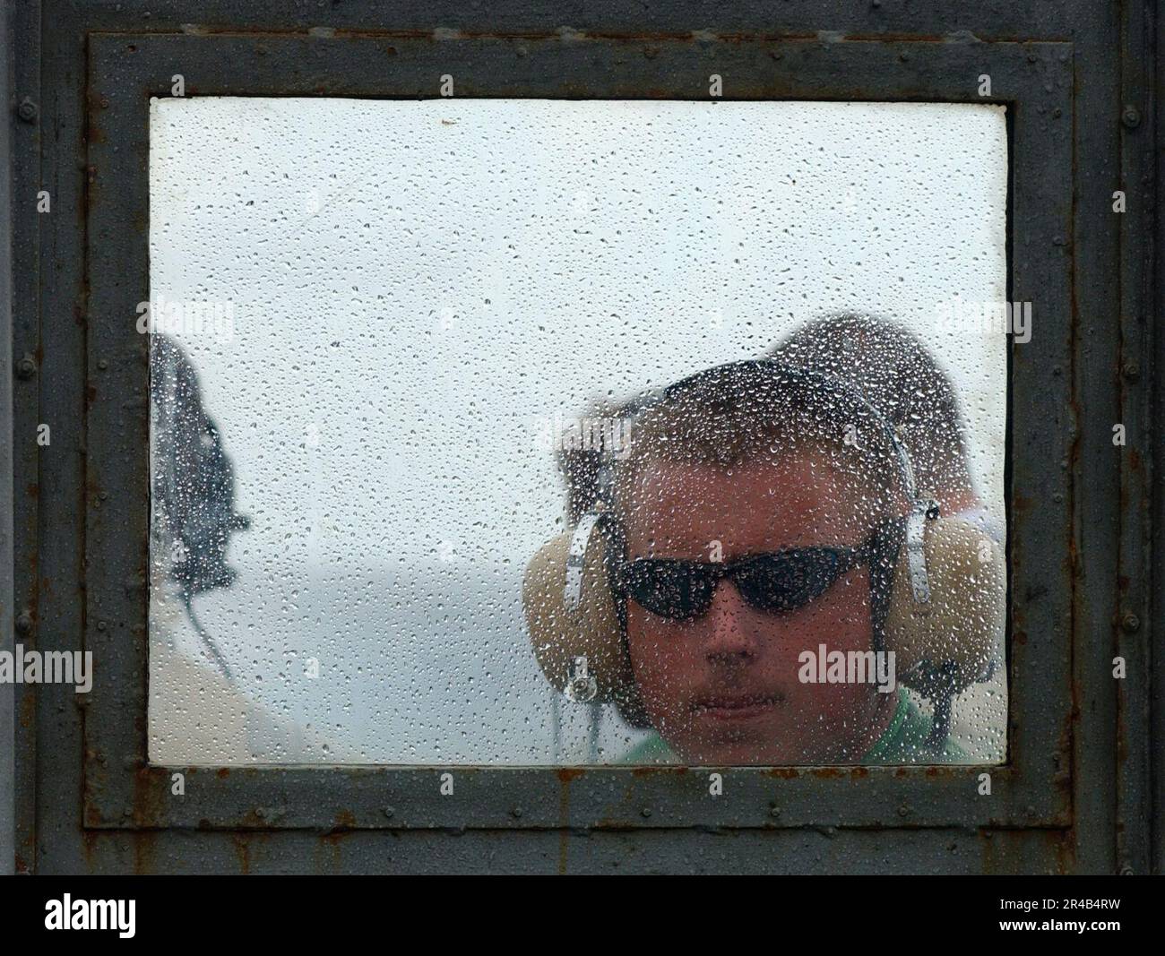 US Navy A Sailor assigned to the Air Department looks through the rain ...