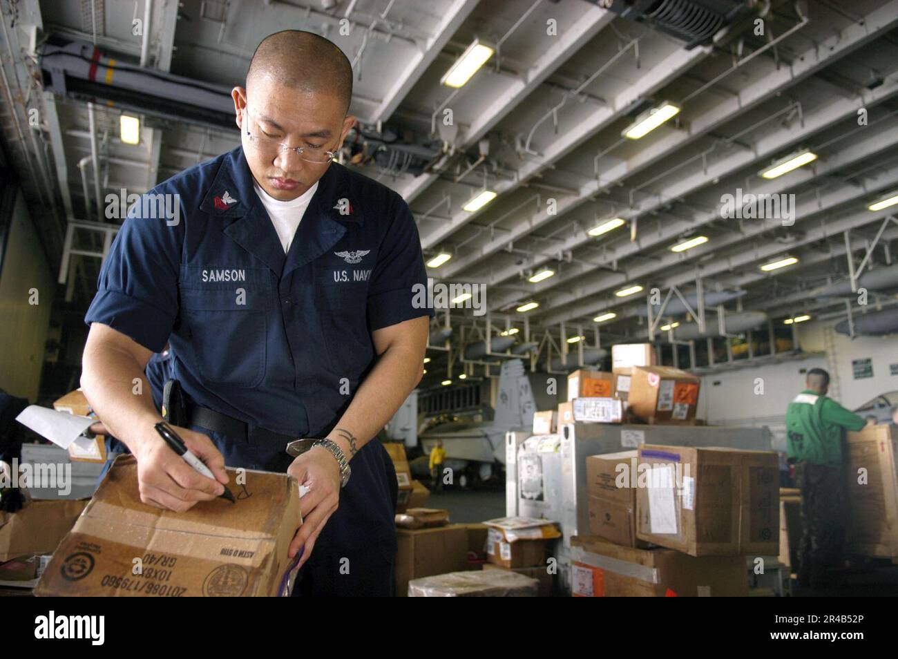 US Navy Storekeeper 1st Class marks a package during the sorting of ...