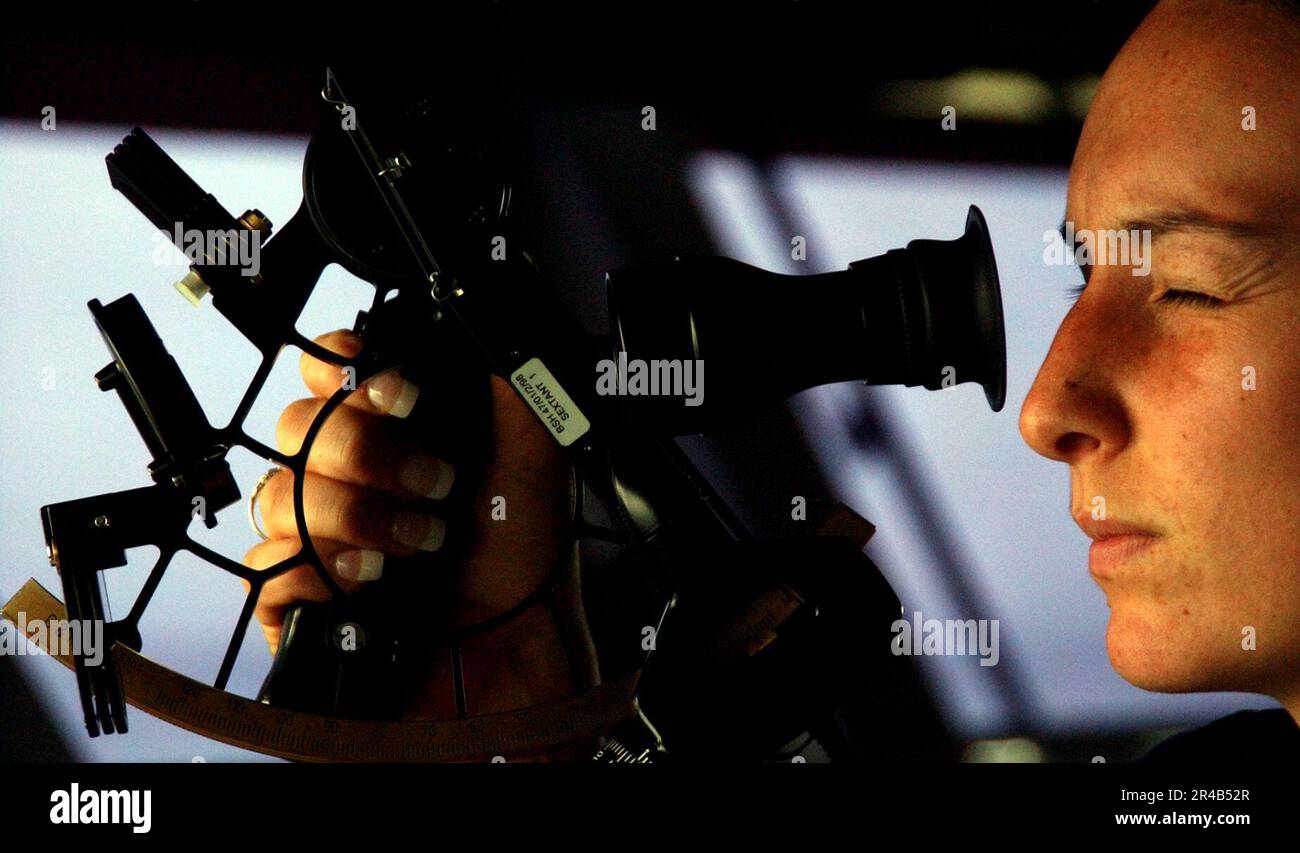US Navy Quartermaster 2nd Class peers through a marine sextant, a ...