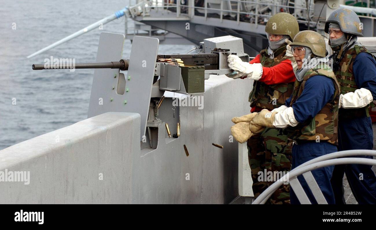 US Navy Airman fires a .50 caliber machine gun while Torpedoman's Mate ...