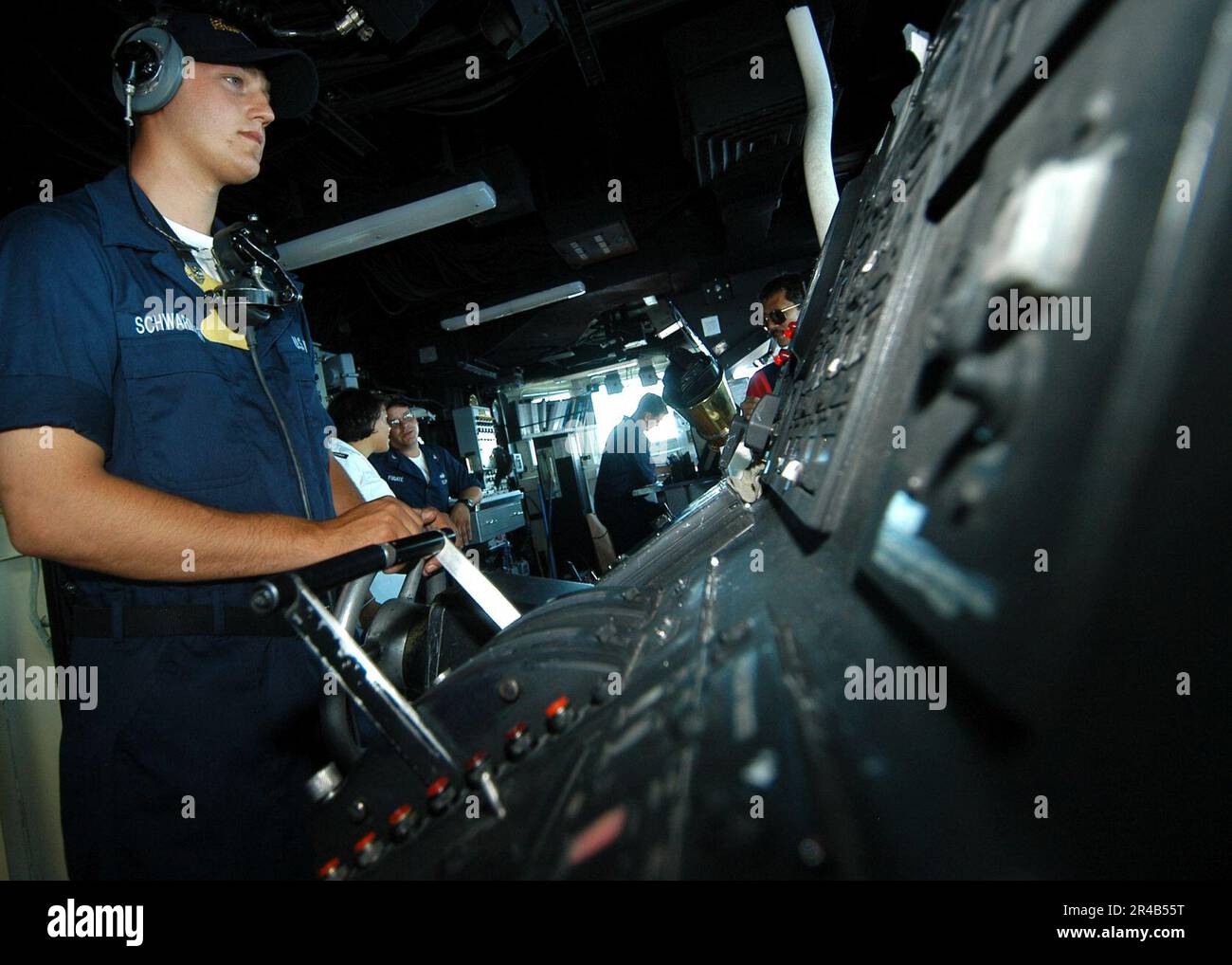 US Navy Seaman mans the helm of the dock landing ship USS Pearl Harbor ...