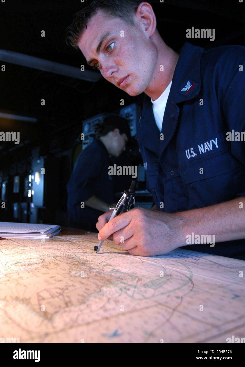 US Navy Quartermaster 2nd Class plots the ship's course aboard the dock ...
