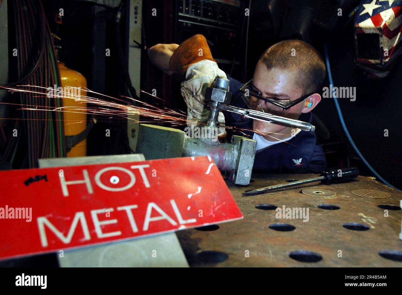 US Navy Hull Technician 3rd Class grinds a catapult hydraulic valve ...