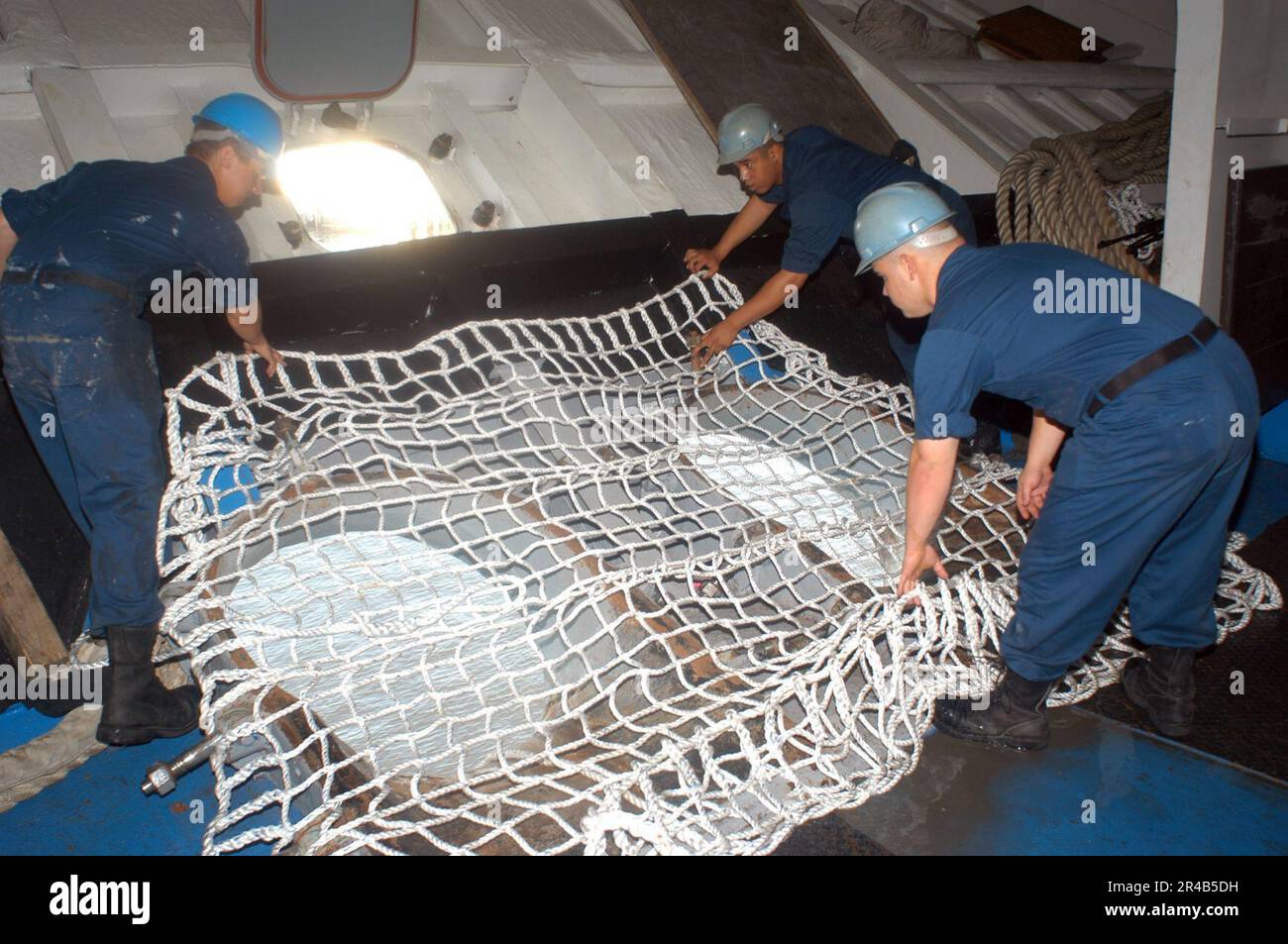 US Navy Deck Seamen, assigned to 1st Division, installs a cargo net ...
