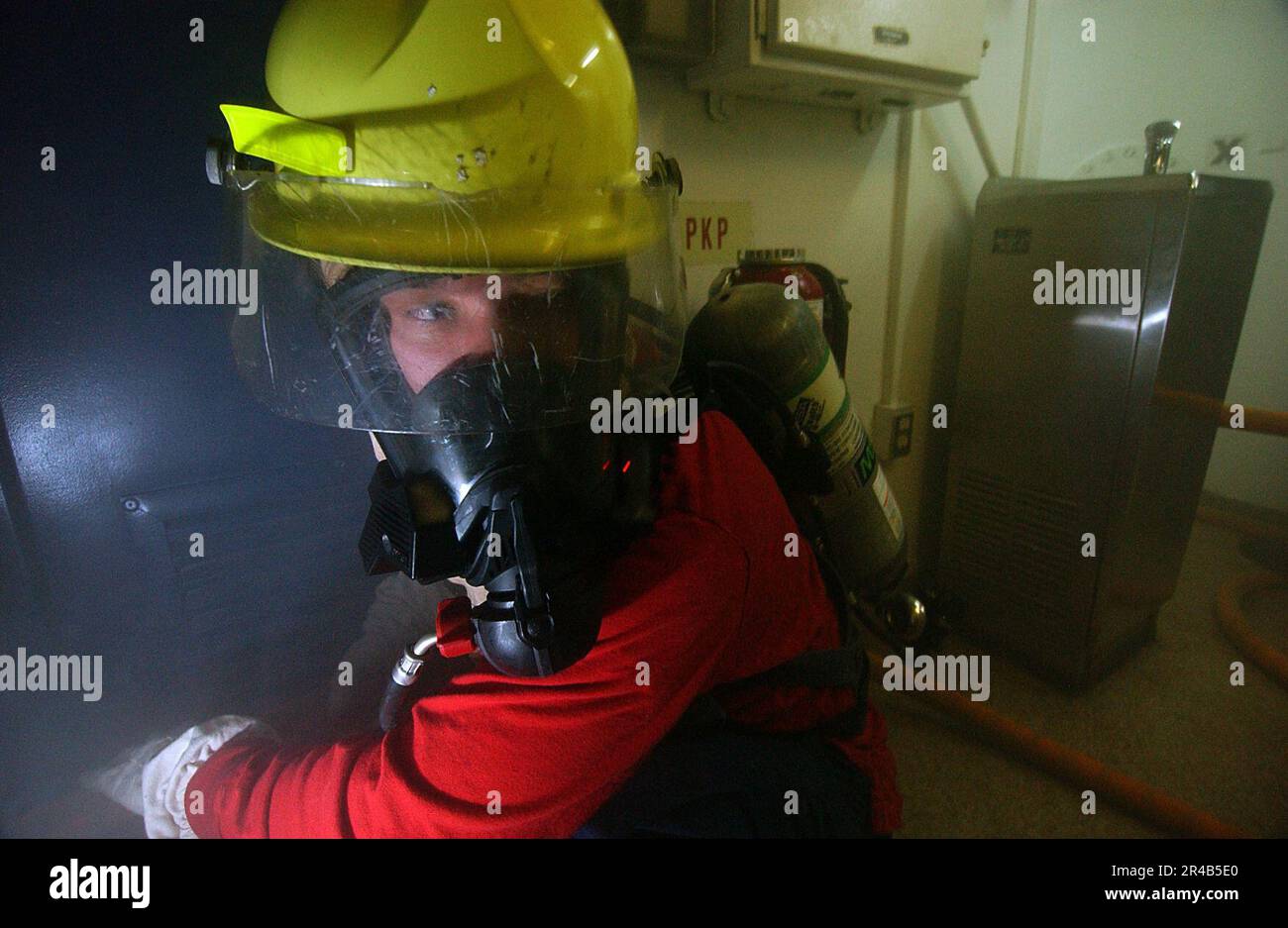 US Navy Petty Officer 2nd Class tends a hose during a firefighting ...