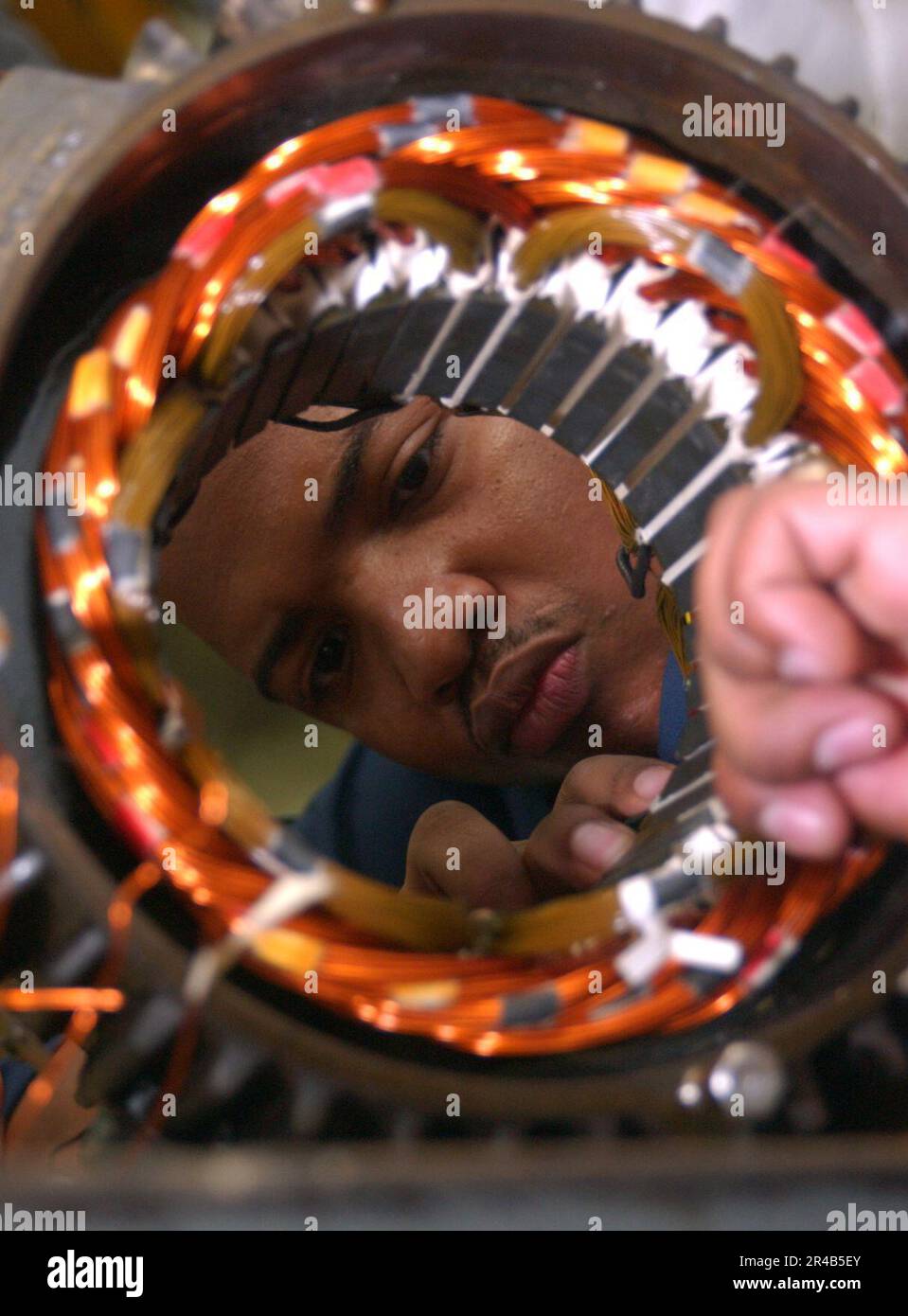US Navy Electrician's Mate rewinds a fan motor for the number four ...