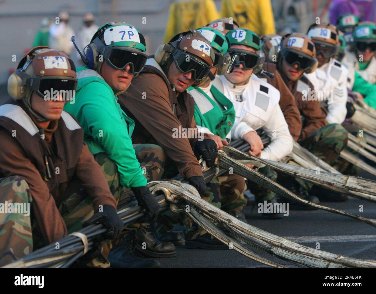 US Navy Several flight deck personnel wait for the orders to rig a ...