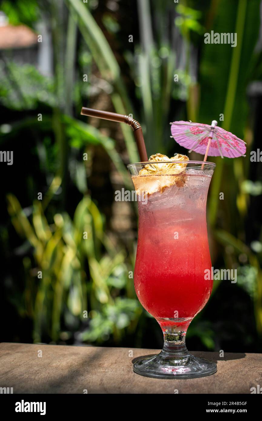 tropical singapore sling cocktail in tall glass at outdoors garden bar ...