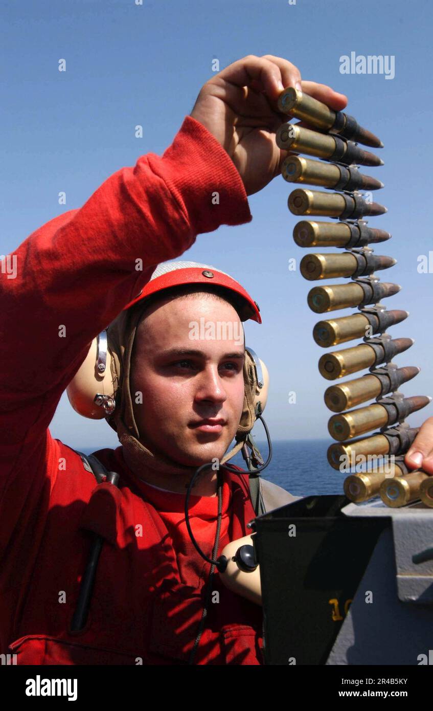 US Navy Aviation Ordnanceman Airman loads ammunition into a .50 cal gun ...