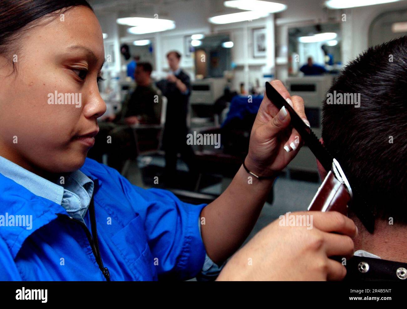 US Navy Ship's Serviceman 3rd Class gives a haircut to a crew member ...