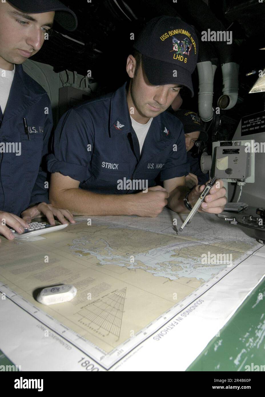US Navy Quartermaster Seaman plots the ship's position before the ...