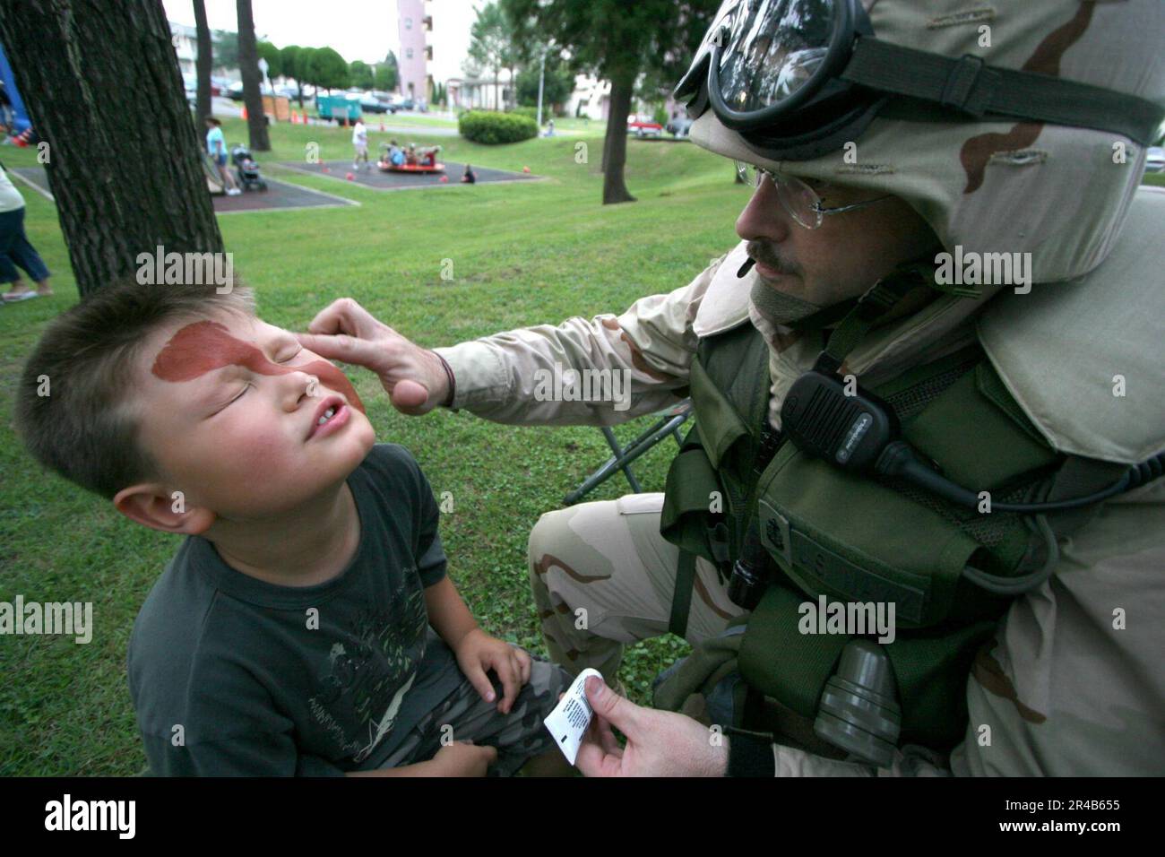 US Navy Chief Master-at-Arms paints the face of a five-year-old with a ...