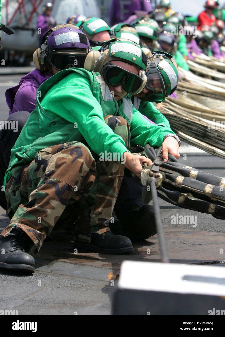 US Navy Flight deck personnel work together while rigging an aircraft ...