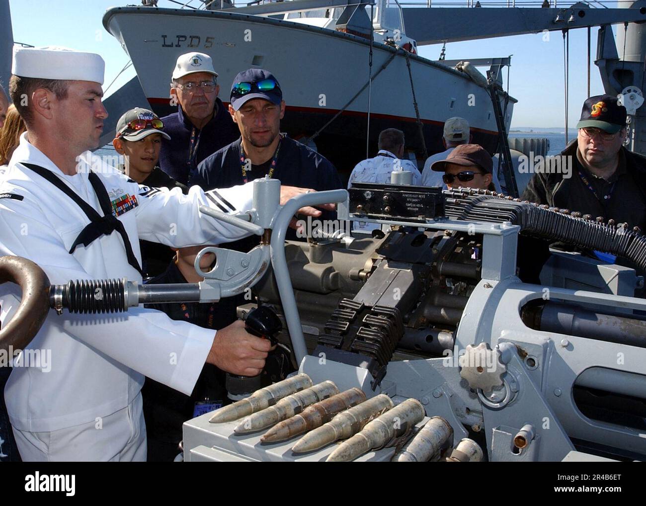 US Navy Gunner's Mate 2nd Class demonstrates procedures on firing a ...