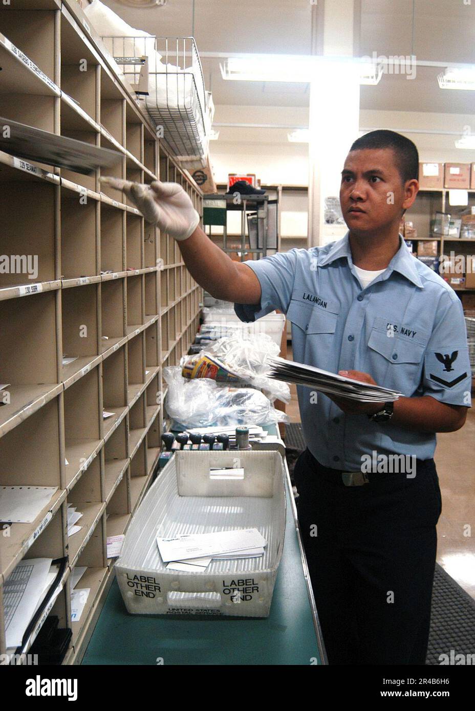 US Navy Ship's Serviceman 3rd Class sorts incoming mail inside the post ...