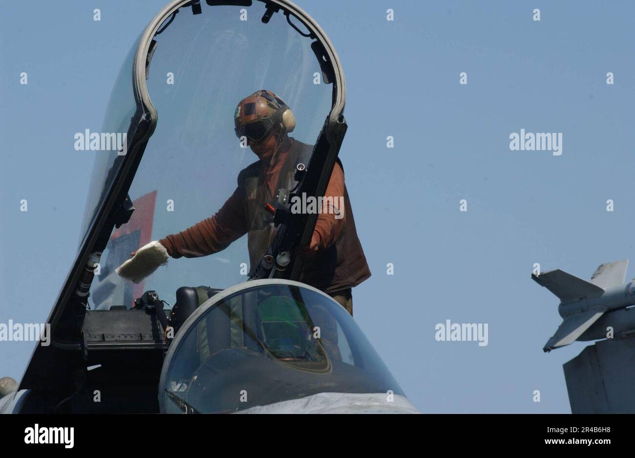 US Navy Aviation Machinist's Mate 3rd Class cleans the canopy of an F-A ...