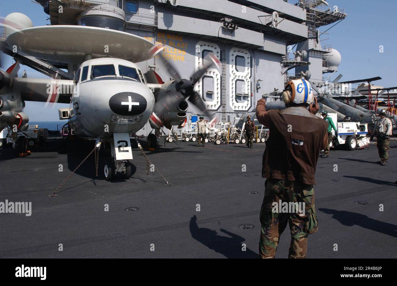 US Navy Airman signals a pilot to start the engines on an E-2C Hawkeye ...