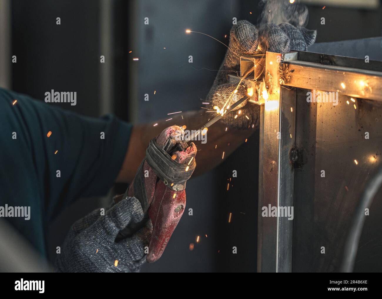 A confident man is performing a welding task, with sparks flying all ...