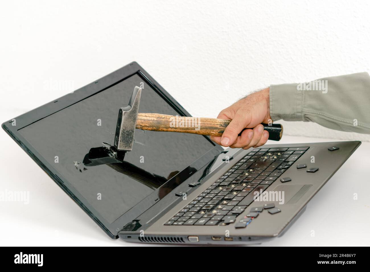 Arm of a man breaking a laptop with a hammer isolated on white ...